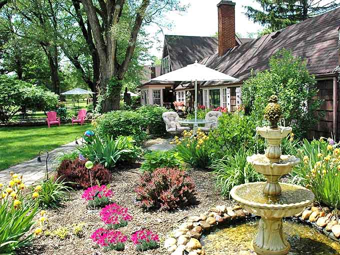 Lazy Cloud's garden fountain bubbles among vibrant flowers, creating a peaceful soundtrack for afternoon daydreams in comfortable outdoor seating.