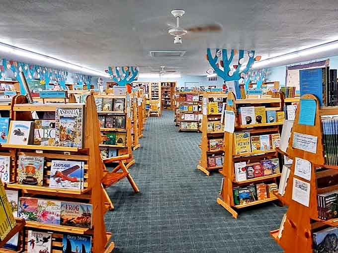 Beneath whimsical blue trees, young readers discover worlds between pages in a children's book section designed to inspire literary adventures.