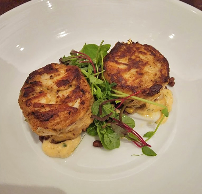 Golden-brown crab cakes that could make a Marylander weep with joy, perched atop a delicate bed of microgreens.