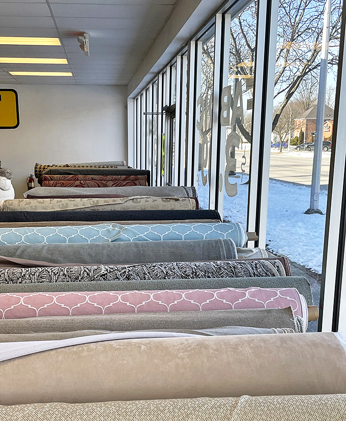 Sunlight streams through the windows, illuminating a rainbow of fabrics that line the walls like colorful soldiers standing at attention.