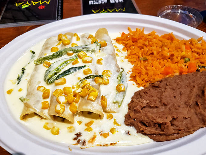 Enchiladas Poblanas smothered in a creamy sauce with corn kernels, served alongside perfectly prepared rice and beans. Comfort food with a Mexican passport.
