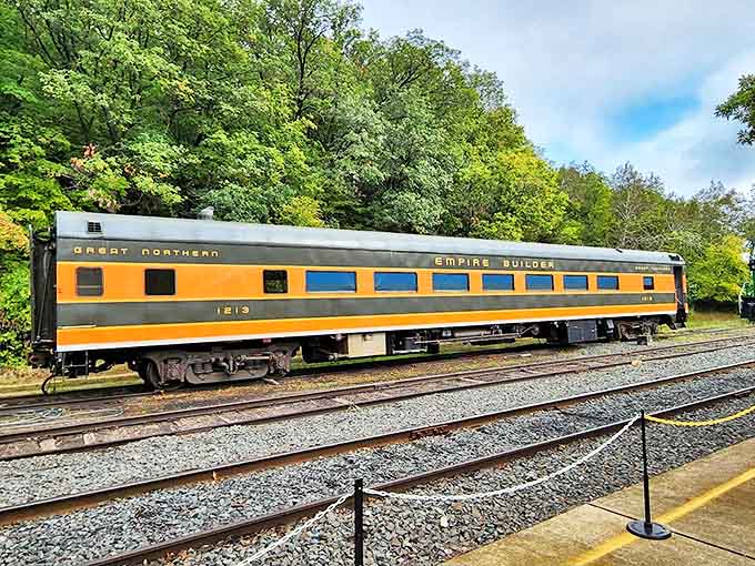 The Great Northern "Empire Builder" passenger car gleams in its iconic orange livery, a restored beauty that once carried travelers across America's northern route.