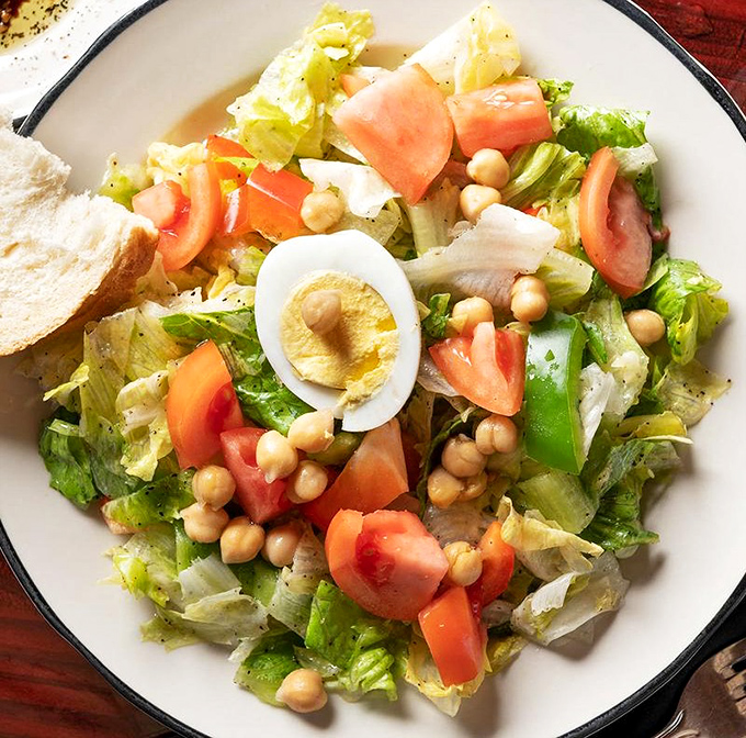 A garden party on a plate where crisp greens mingle with tomatoes, eggs, and chickpeas, all dressed in house-made Italian finery.
