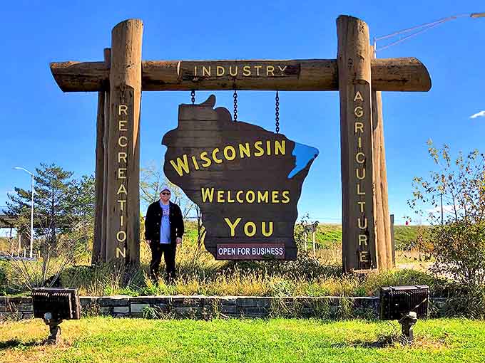 A traveler pauses at Wisconsin's wooden welcome sign, marking the moment when vacation officially begins and worries fade away.