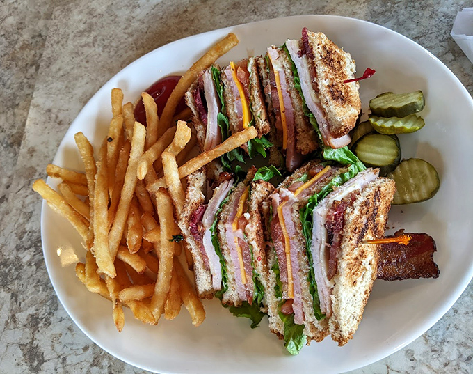The club sandwich &ndash; architecture you can eat! Three stories of toasted bread, meat, and veggies secured with toothpicks and served with golden fries.
