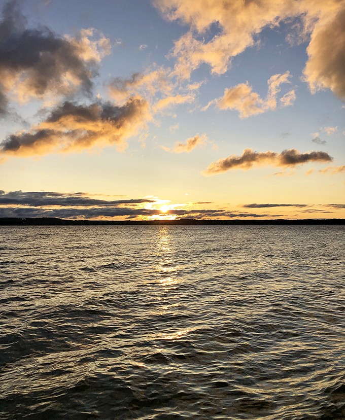 Golden hour magic transforms Elk Lake into liquid amber &ndash; Michigan sunsets that rival any tropical paradise.