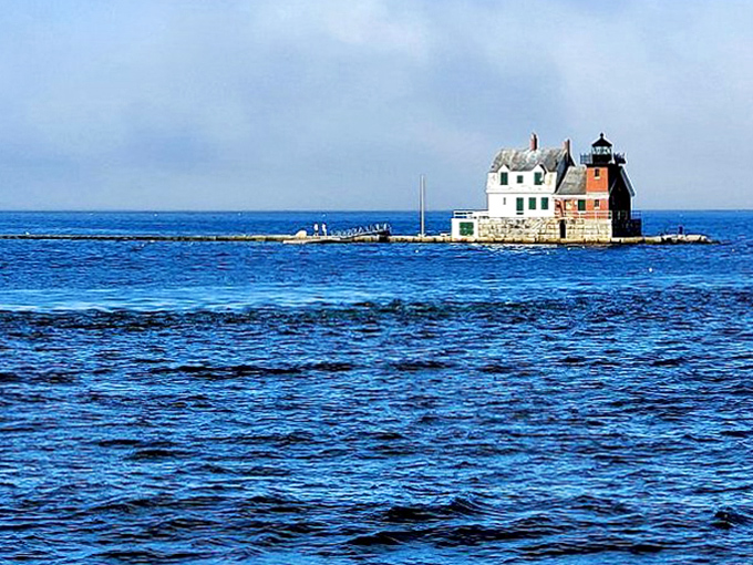 The lighthouse stands in splendid isolation, surrounded by the deep blues of Penobscot Bay on all sides.