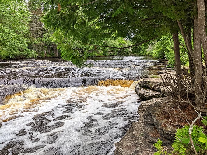Rapid River Falls spreads wide across layered shelves, showing off the rusty colors that make Michigan waterfalls so unique.