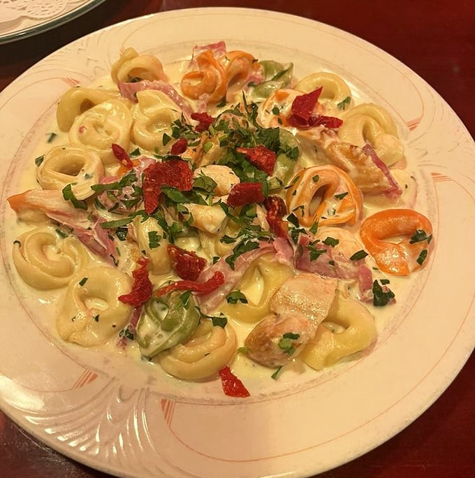 Tortellini swimming in creamy sauce with colorful vegetables &ndash; like little pasta presents waiting to be unwrapped by your fork.