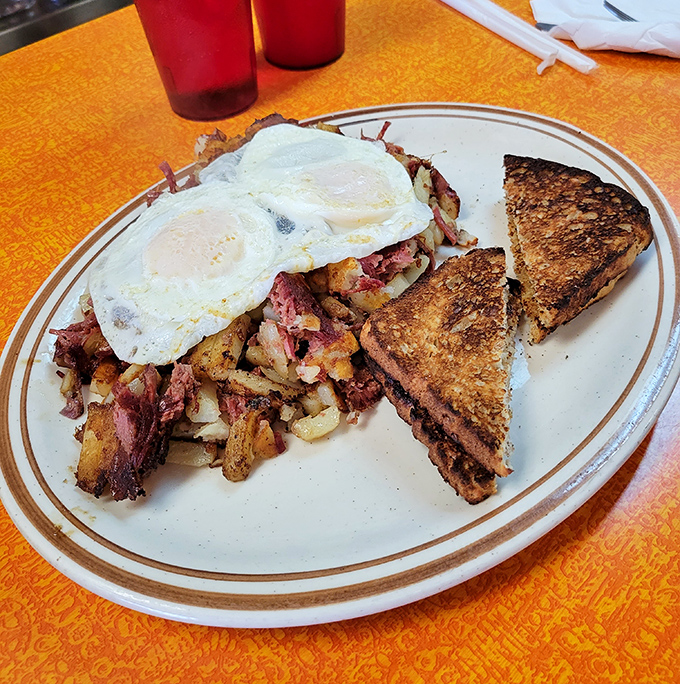 The holy trinity of breakfast perfection: corned beef hash with the ideal crisp-to-tender ratio, eggs with runny yolks, and toast for sopping.