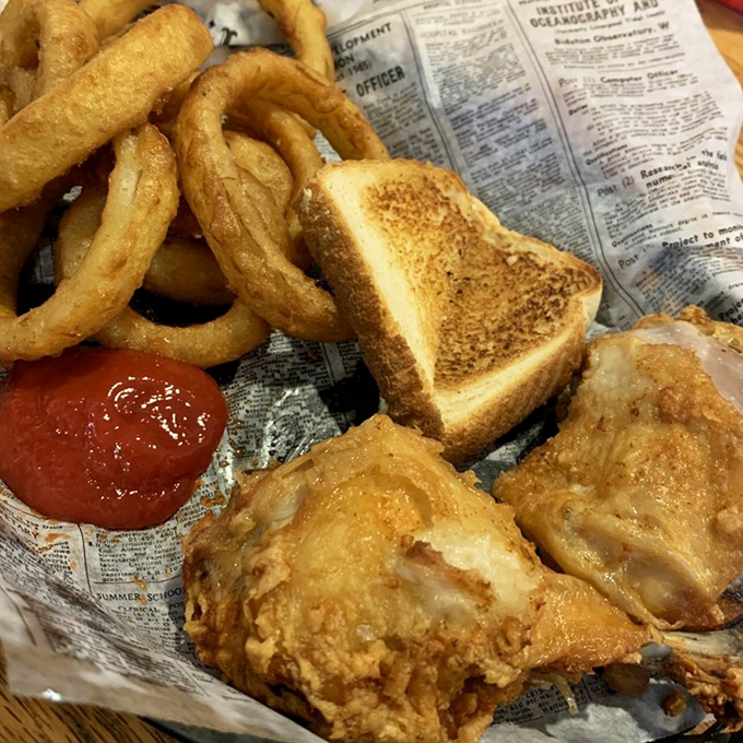 Simple pleasures done right &ndash; crispy onion rings and perfectly seasoned chicken served on newspaper, because some traditions just work.