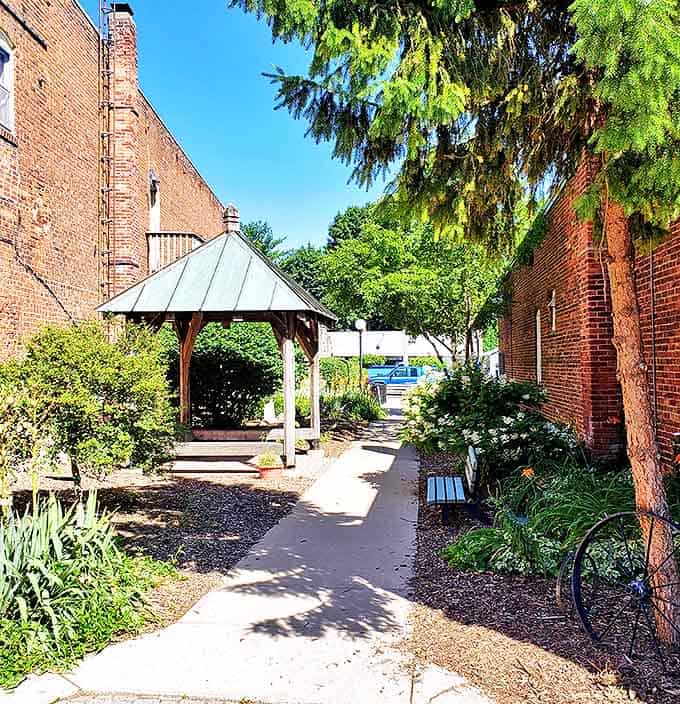 A peaceful garden pathway leads between brick buildings, offering a quiet moment of reflection in the midst of downtown exploration.