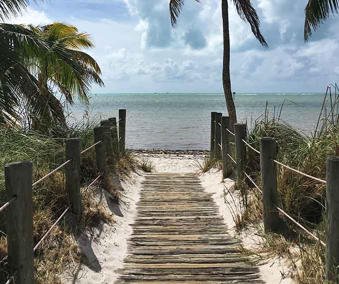 Wooden boardwalks lead to hidden beaches where palm trees sway and the Caribbean-blue water beckons you closer.