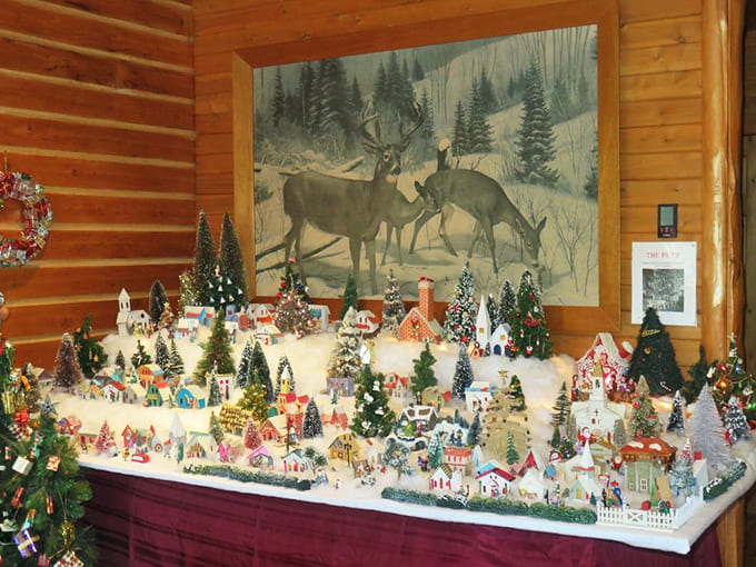 A winter wonderland in miniature form sits beneath a majestic deer painting. This tiny town has more Christmas spirit than cities ten times its size.