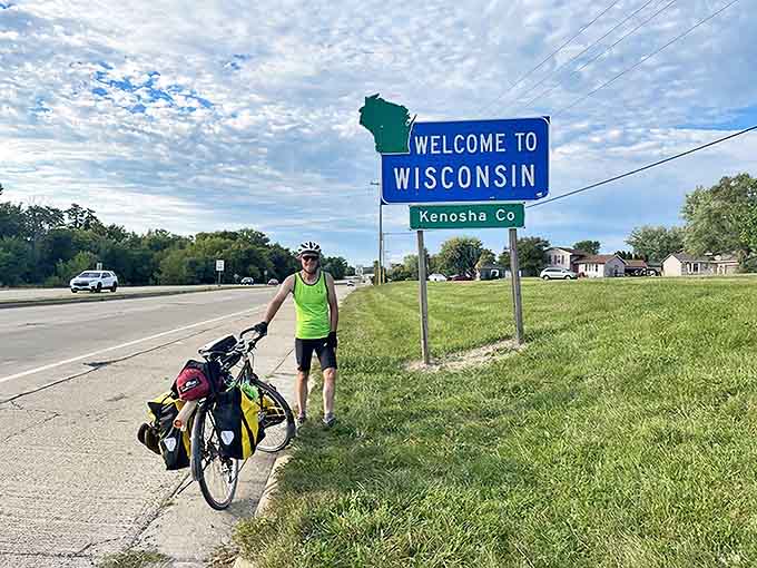 A determined cyclist celebrates reaching Wisconsin's border, the first of many triumphant moments awaiting on the state's scenic trails.