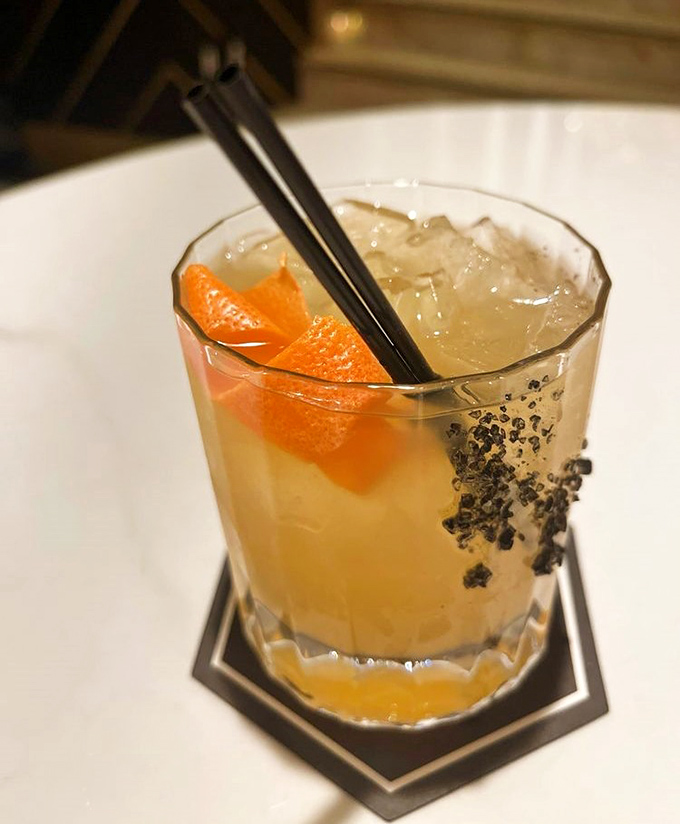 Amber liquid, citrus peel, and what appears to be black salt &ndash; this isn't just a cocktail, it's a conversation starter.