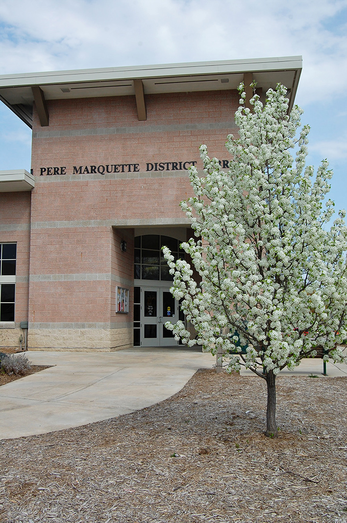 The Pere Marquette District Library stands as a testament to Clare's commitment to community and learning, its entrance framed by spring blossoms.