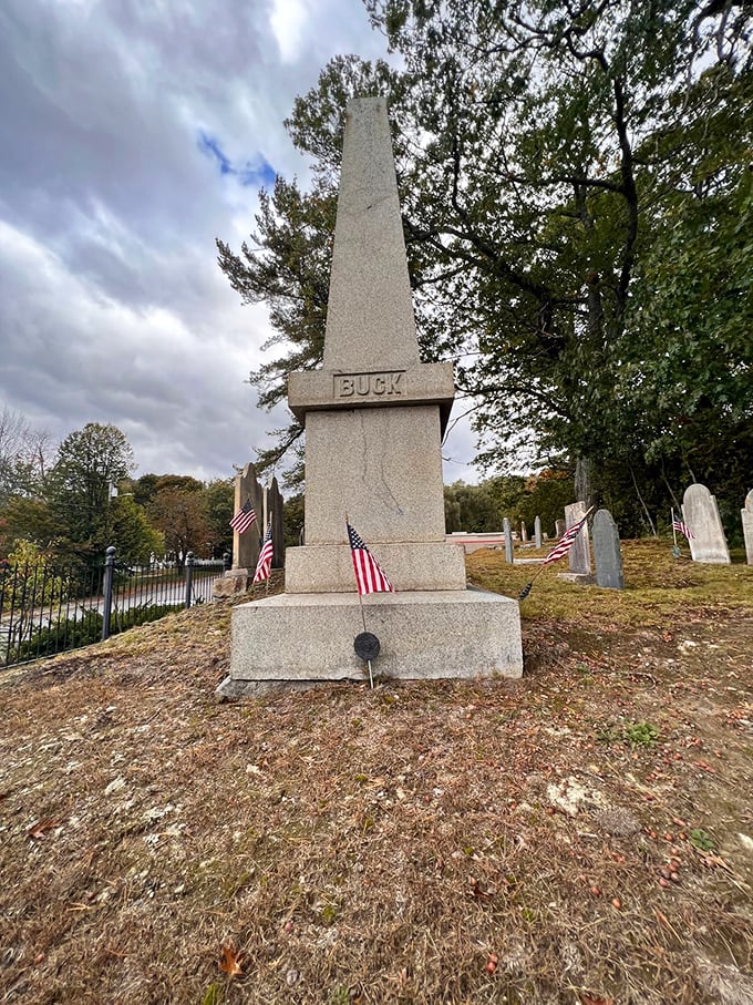 Small American flags surround the monument, a patriotic tribute to Colonel Buck's military service that contrasts with the darker legend of his alleged cruelty.