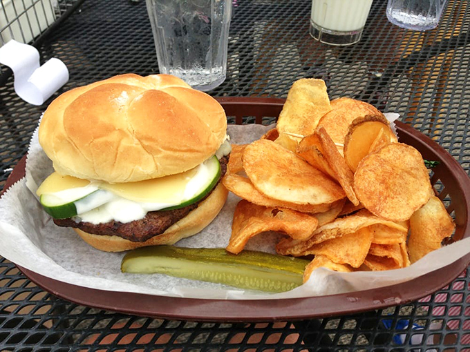 Burger perfection with pickle prominence &ndash; a juicy patty topped with fresh vegetables on a soft bun, accompanied by house-made potato chips.