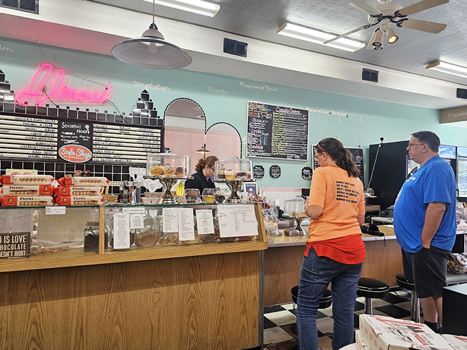 The counter area glows with vintage charm, where the neon "Alinosi" sign serves as a beacon for those seeking sweet salvation.
