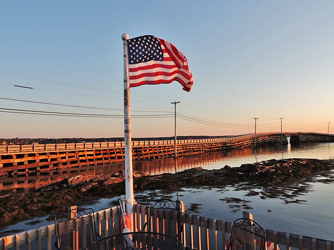 The American flag stands proud near the bridge, both symbols of ingenuity and resilience.