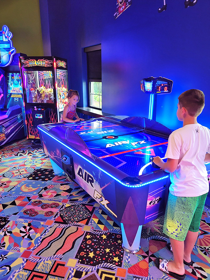 Children face off across the air hockey table, their concentration suggesting Olympic medals rather than arcade bragging rights are at stake.