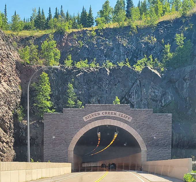 Vehicles appear tiny against the massive cliff face, offering perspective on just how ambitious the tunnel project was when engineers first conceived it.