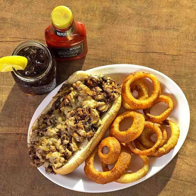 The philly cheesesteak loaded with beef, mushrooms, and melted cheese alongside crispy onion rings is messy, indulgent, and absolutely worth every napkin you'll need.