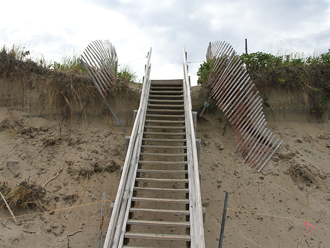 These weathered steps have witnessed countless sandy footprints, leading beachgoers from dune to shore through changing seasons.