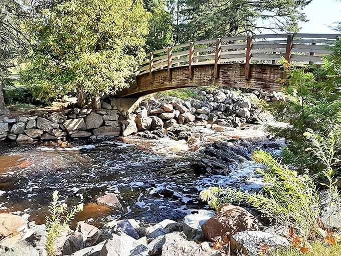 Nature's raw power on display as water rushes beneath a wooden footbridge at Pattison State Park, carving its ancient path through Wisconsin bedrock.