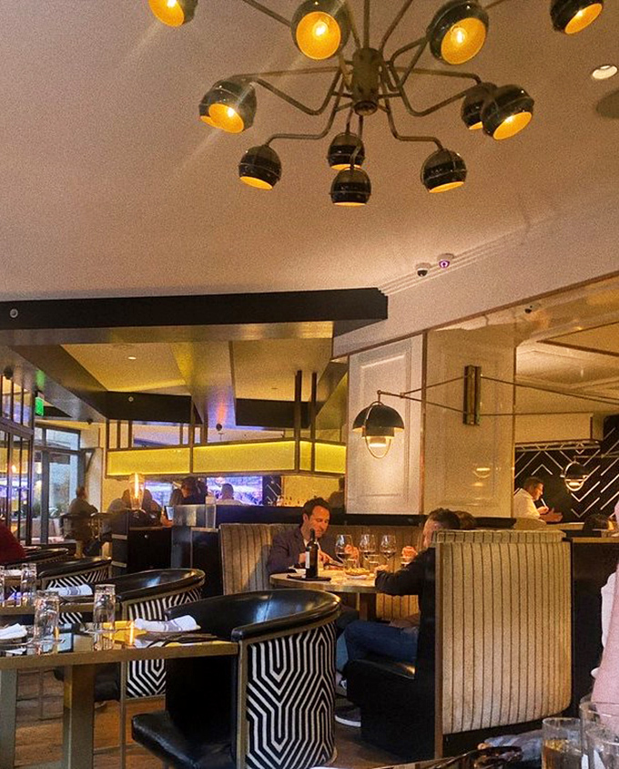 Elegant booths and strategic lighting create intimate islands in a sea of sophisticated conversation.