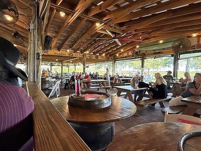Under rustic wooden beams, visitors gather at picnic tables where conversations flow as freely as the wine in this open-air paradise.