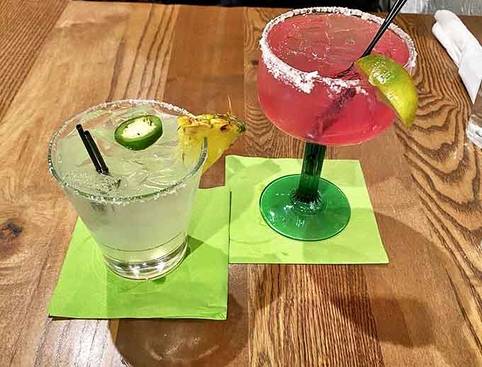 Margaritas that mean business – one classic lime with a jalapeño kick, one vibrant prickly pear, both rimmed with salt and promising good times ahead.
