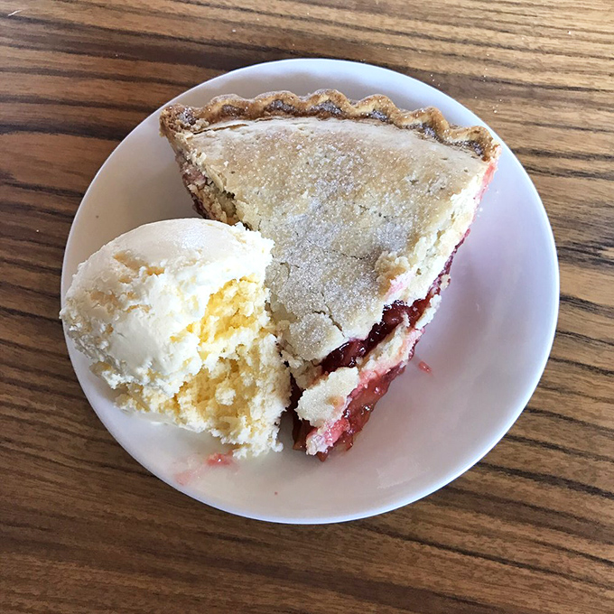 Strawberry rhubarb pie with ice cream melting into warm filling &ndash; the perfect sweet-tart balance that makes Minnesota fruit pies legendary. 