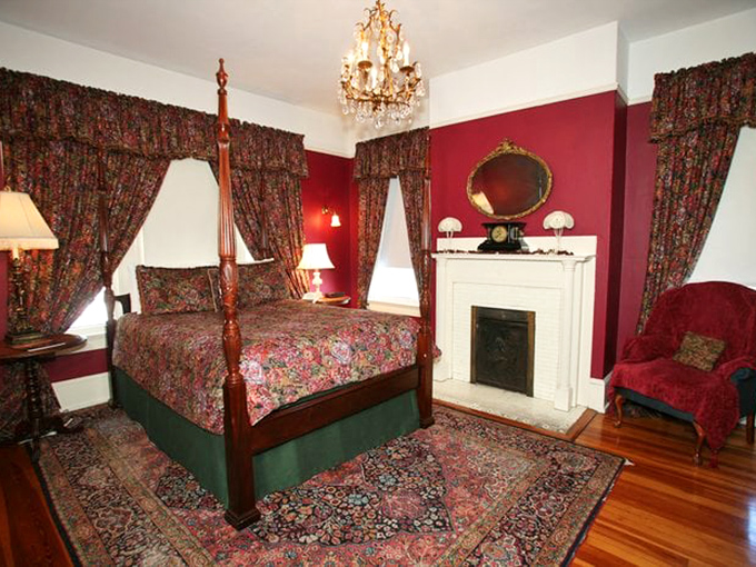 Rich crimson walls embrace period furnishings in the Hoyt Suite, creating a luxurious retreat worthy of Victorian nobility.