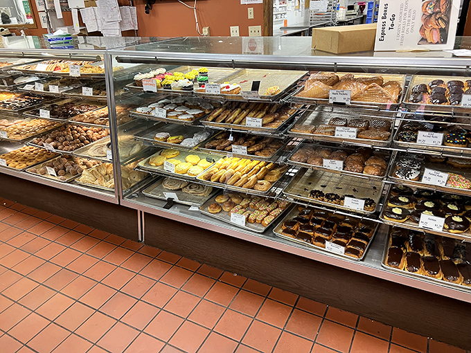 The display case stretches like a treasure chest of pastries, each shelf offering new temptations for the sweet-toothed explorer.