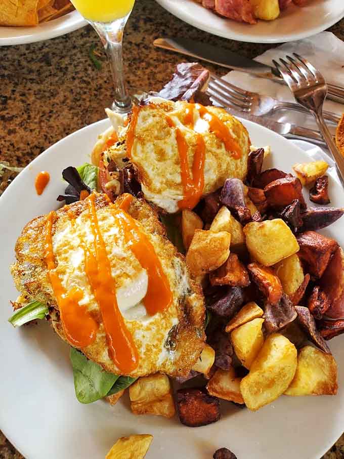 Breakfast gets serious with crispy potatoes and eggs Benedict topped with hollandaise and hot sauce, because mornings deserve this kind of attention.