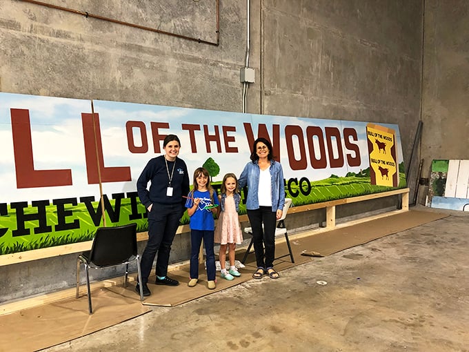 Visitors pose with the "Bull of the Woods" mural, a recreation of vintage tobacco advertisements that gives the bridge its distinctive character.