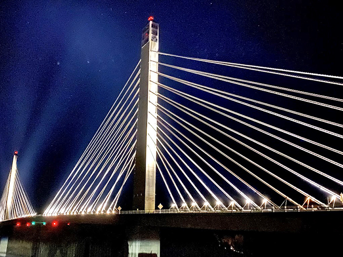 At night, the bridge transforms into a luminous sculpture, its lights reflecting off the dark waters of the Penobscot River below.
