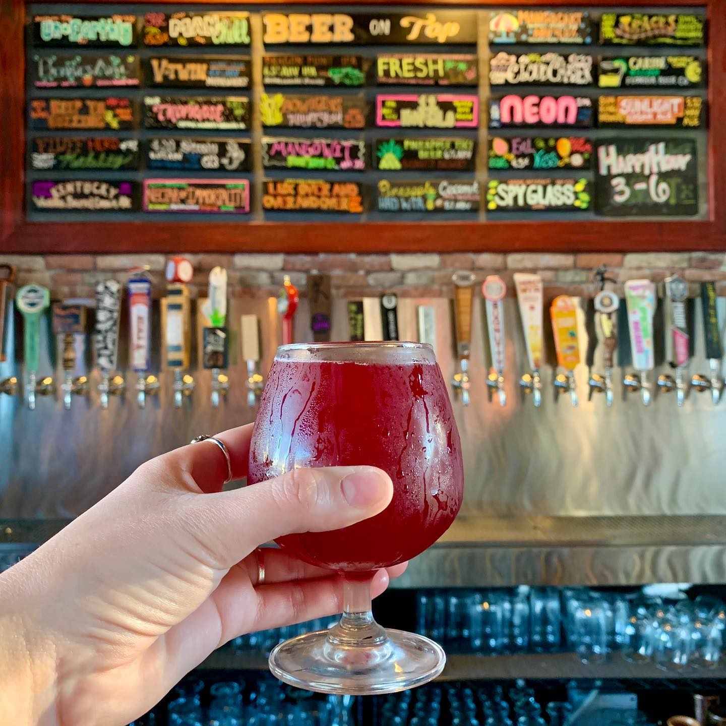A glass of cocktail drink with an extensive craft drinks at the background