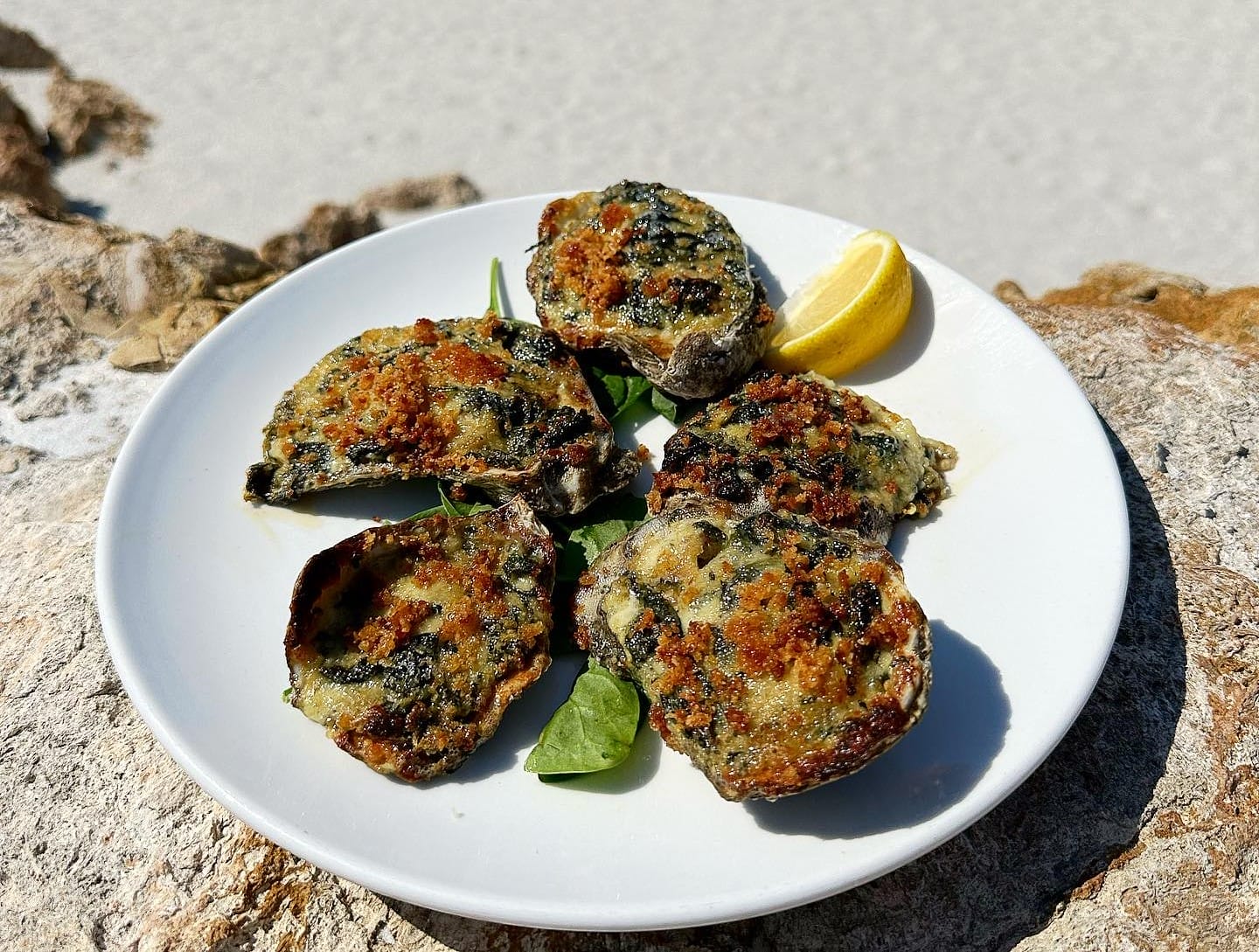 a perfectly cooked oyster rockfeller with lemon on the side