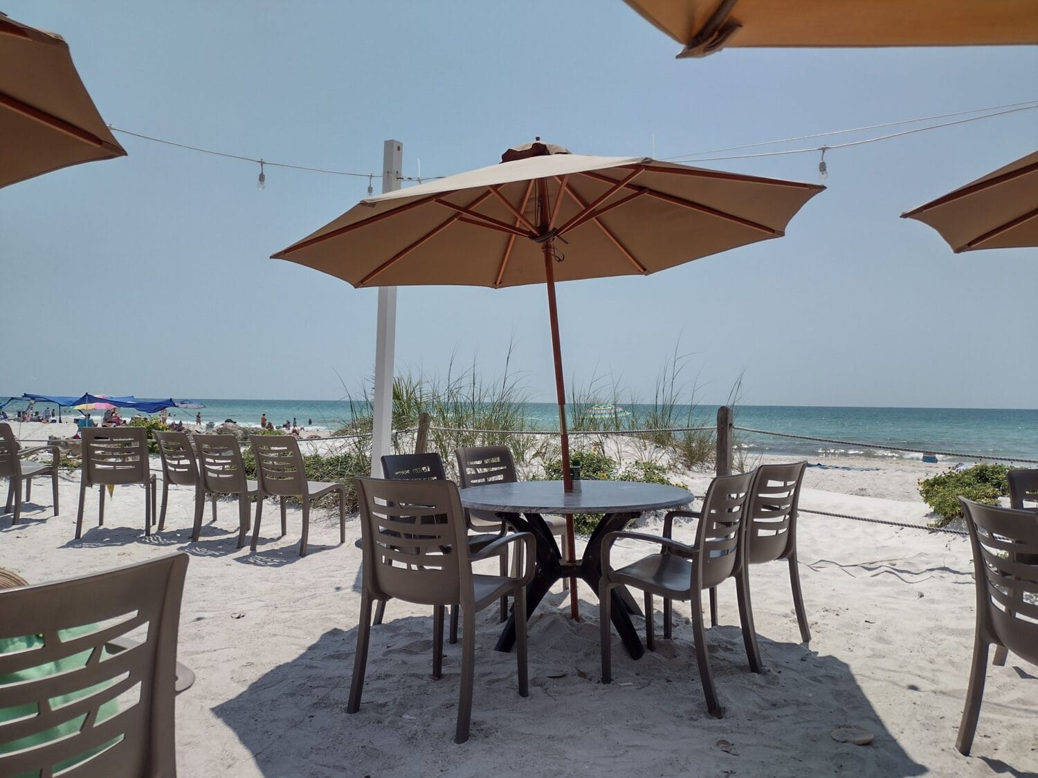 a picturesque view of the ocean with tables and chairs for dining along with an umbrella