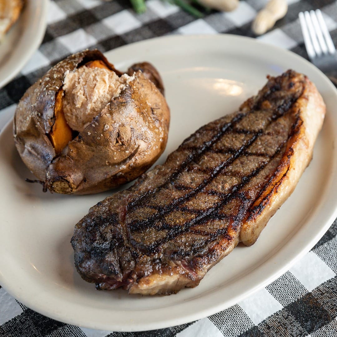 a plate of juicy steak and a potato on the side