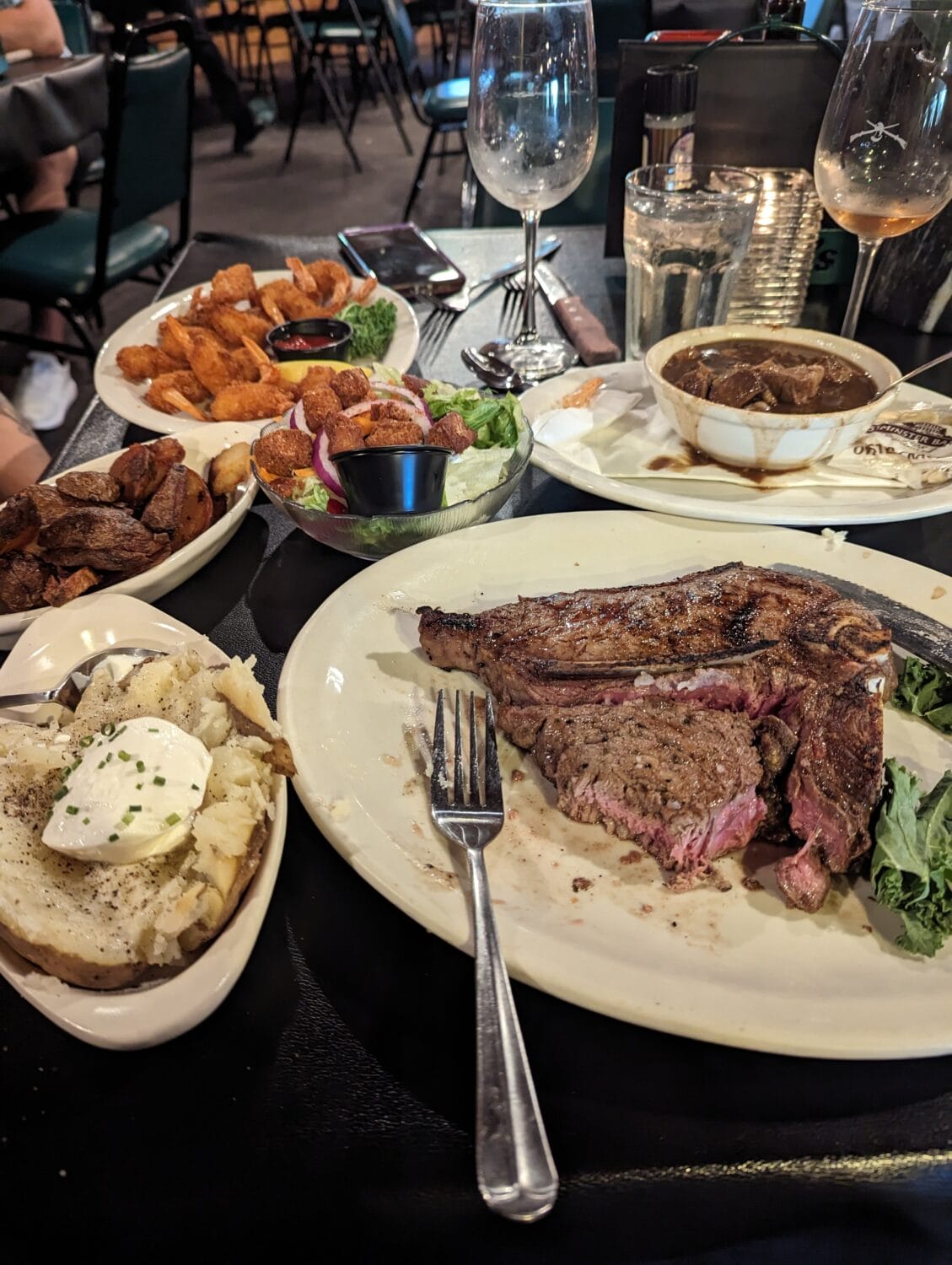 a rustic restaurant table laden with a variety of dishes including steak salad and potatoes