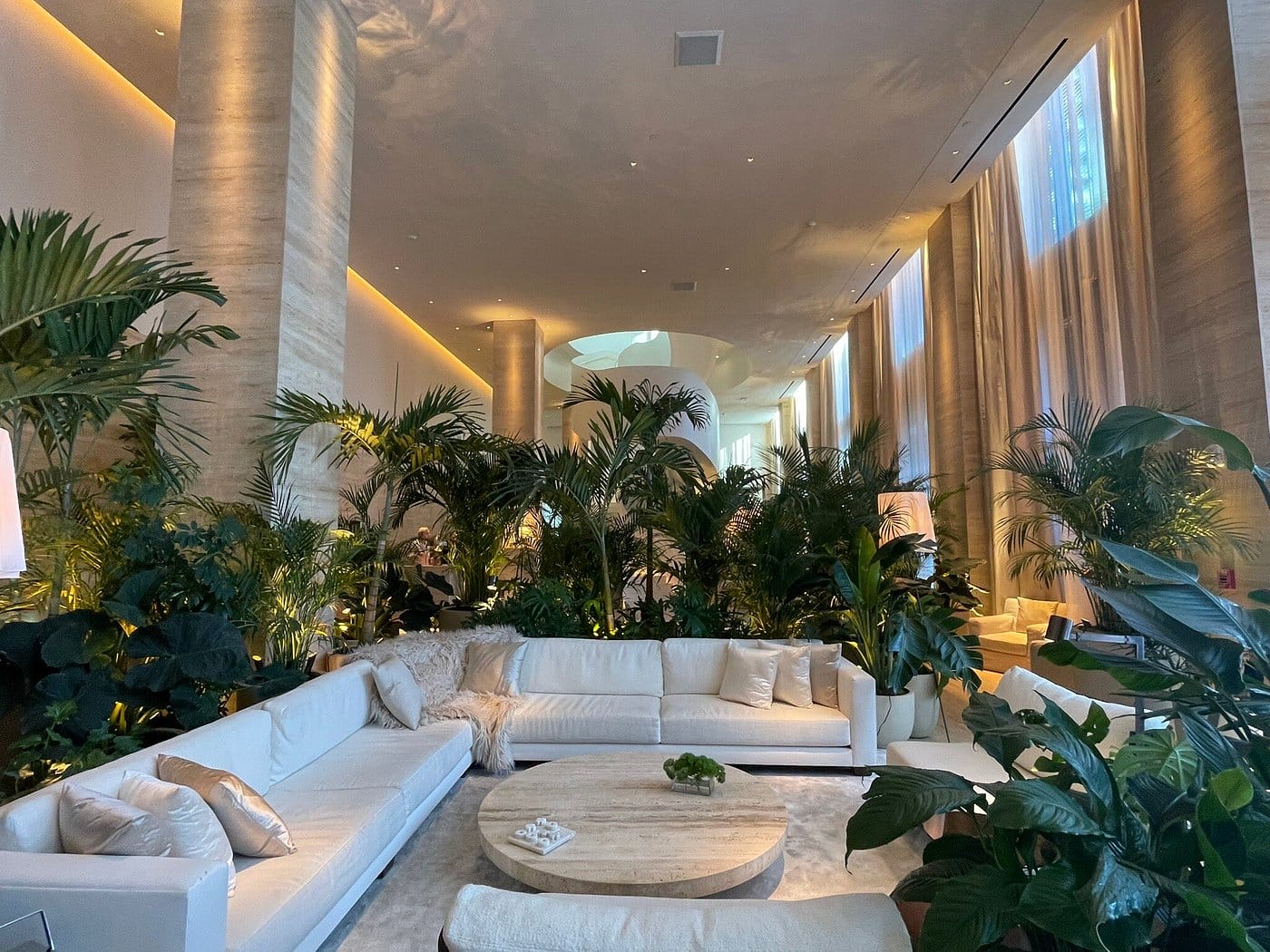 high ceiling lobby with tropical plants surround the long chairs