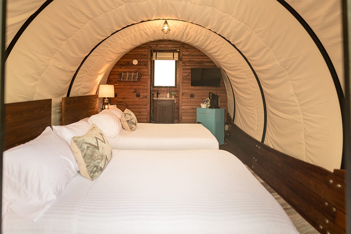 interior view of a covered wagon lodging showing two beds and rustic wooden decor
