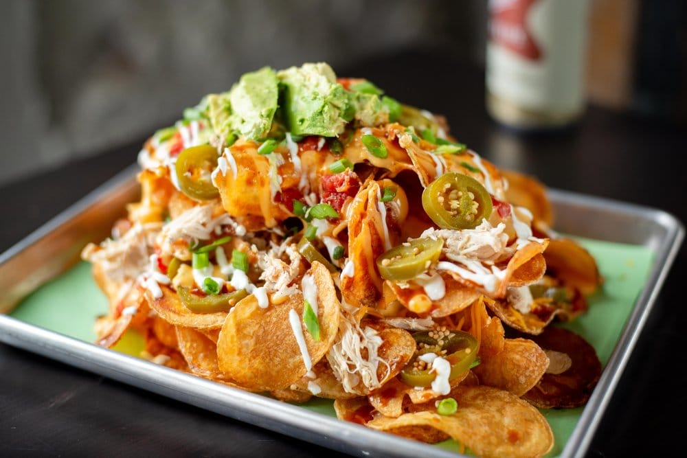 redneck nachos with chips smoked chicken bbq sauce sour cream tomatoes and green onions