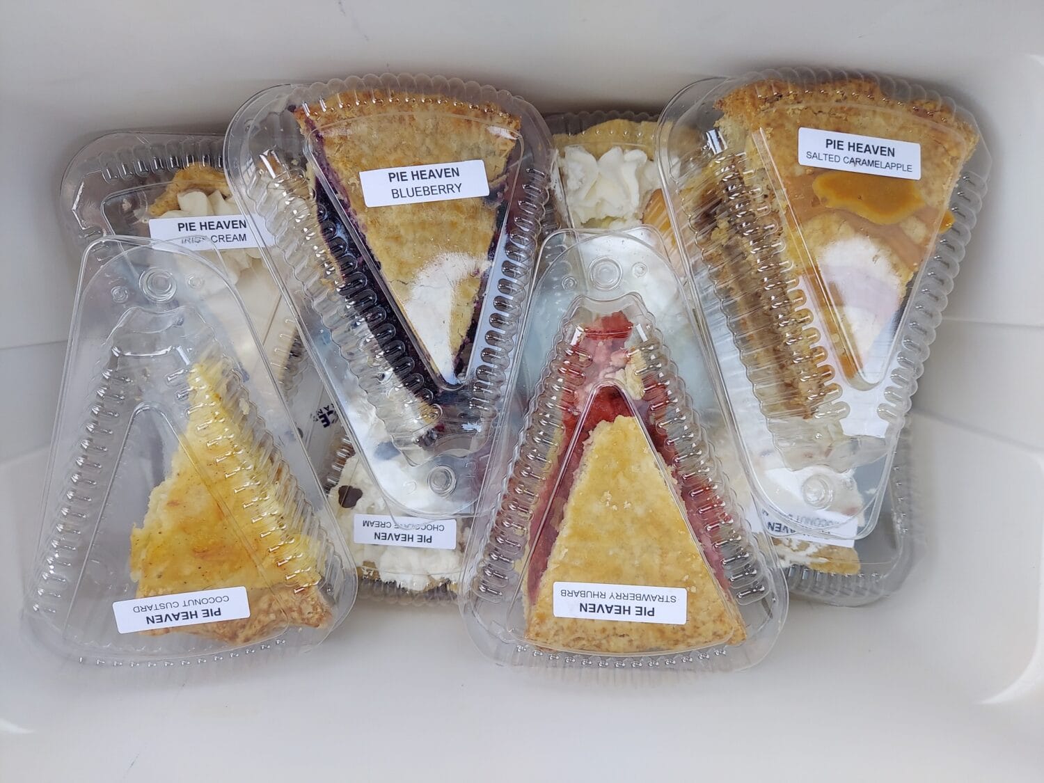 slices of various sweet flavors of pies wrapped in plastic for take out