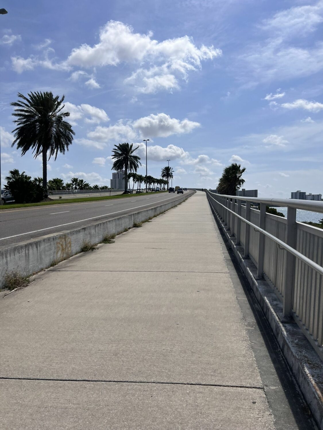 the trail leading up to the bridge where cars are seen passing by on the left side