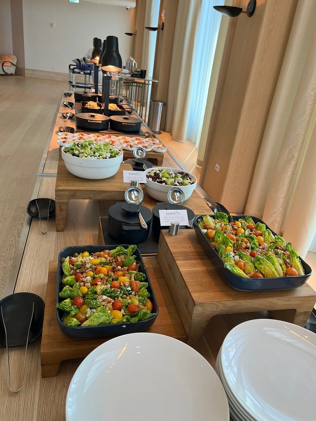 a long table of various food with plates and serving utensils